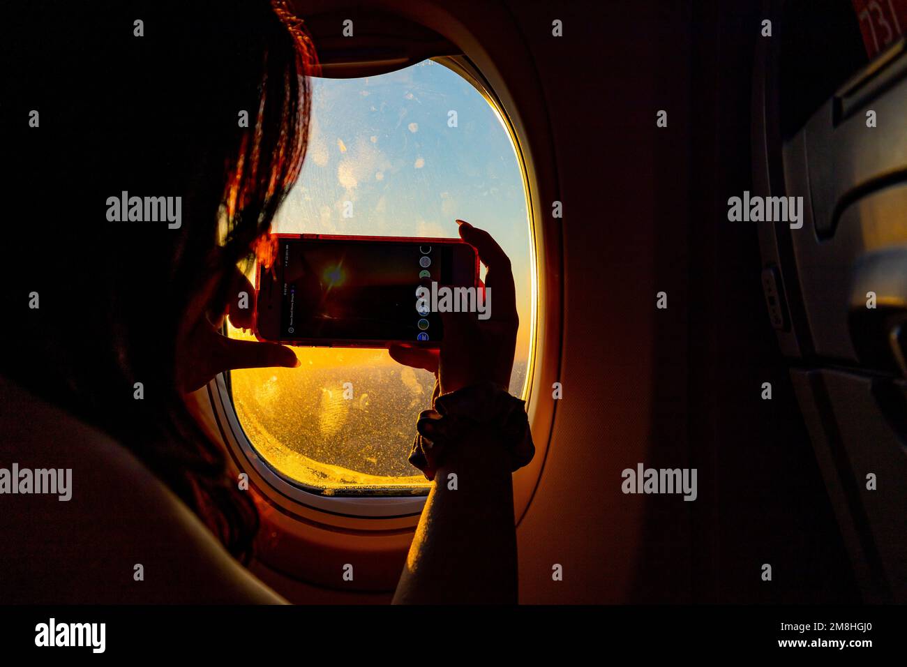 A young female taking a photo of the sunset out the window of an ...
