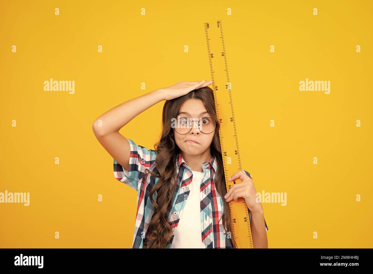 Kid height measure, growth measurement. Funny face. School girl holding ...