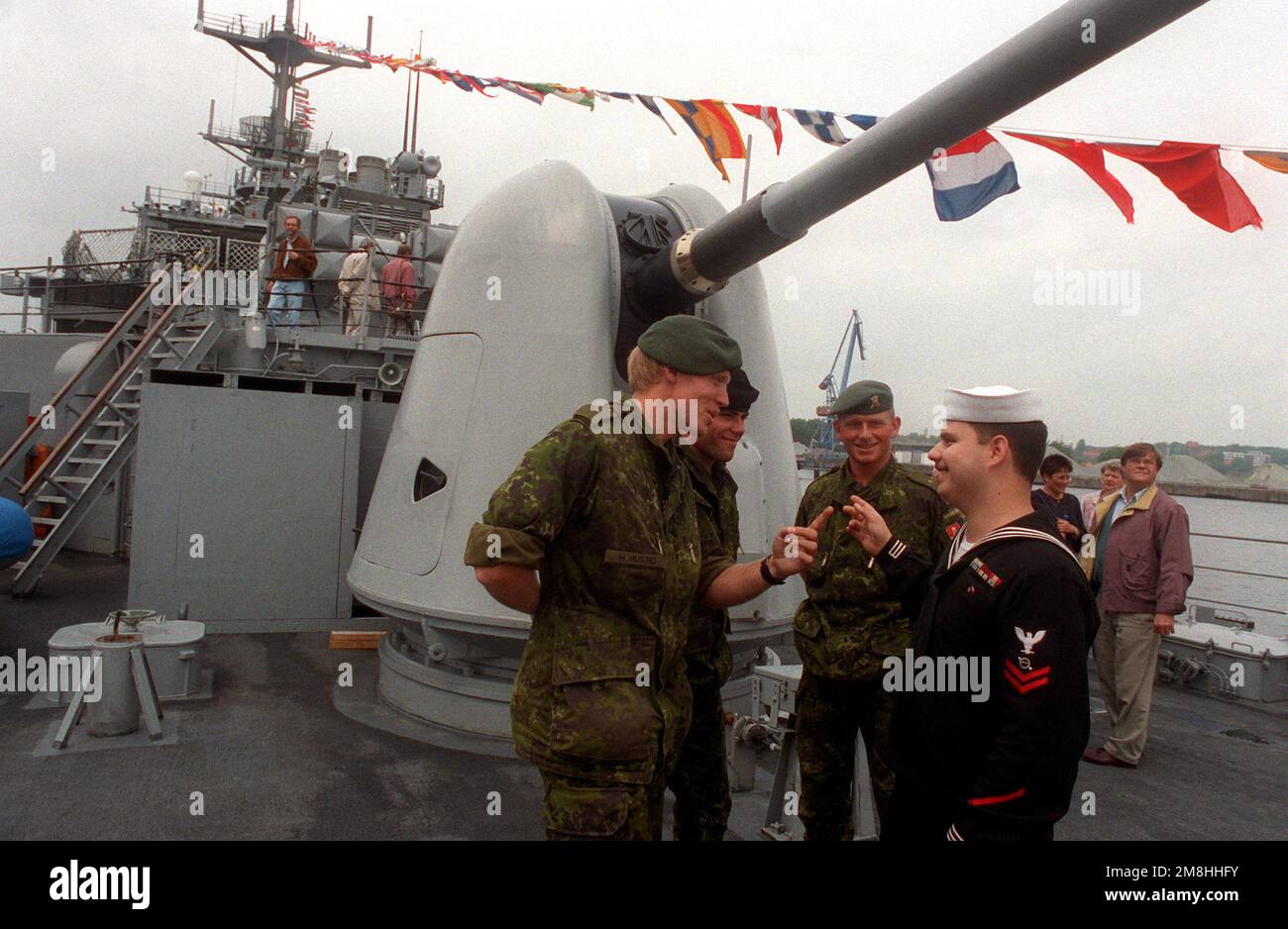 A sailor speaks to foreign military personnel touring the destroyer USS ...