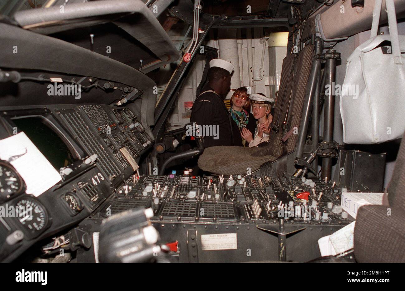 A sailor shows visitors the cockpit of a helicopter aboard the guided ...