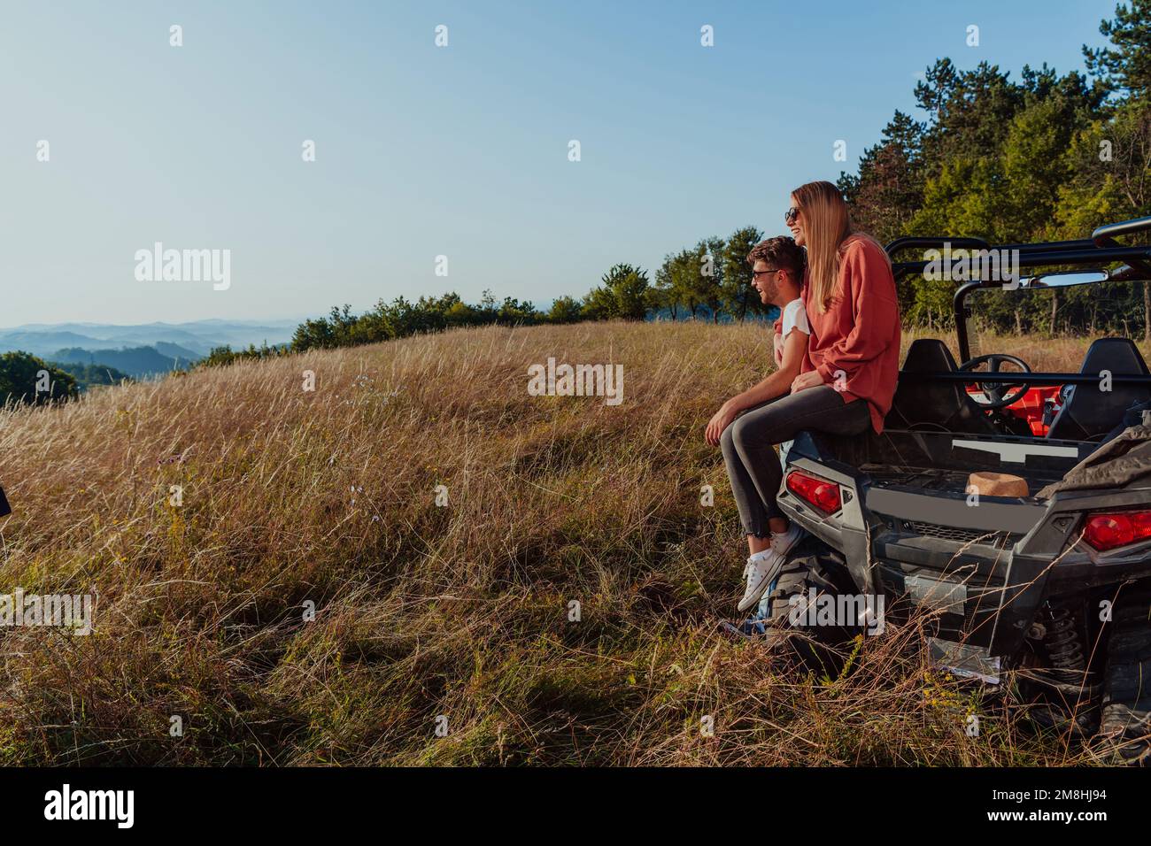 Young happy excited couple enjoying beautiful sunny day while driving a off road buggy car on ...