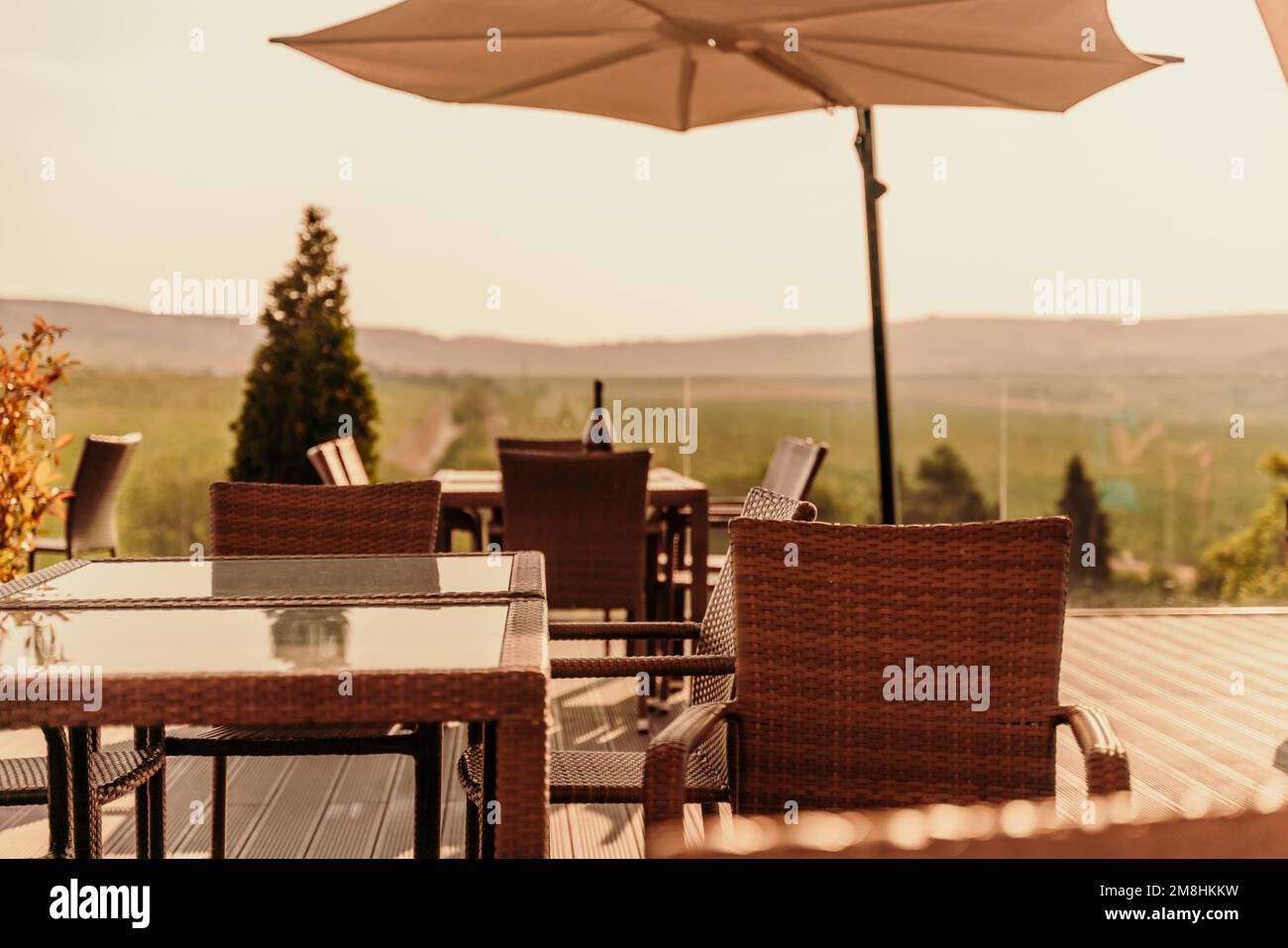 Empty tables in a street cafe overlooking mountains and trees. Sun ...