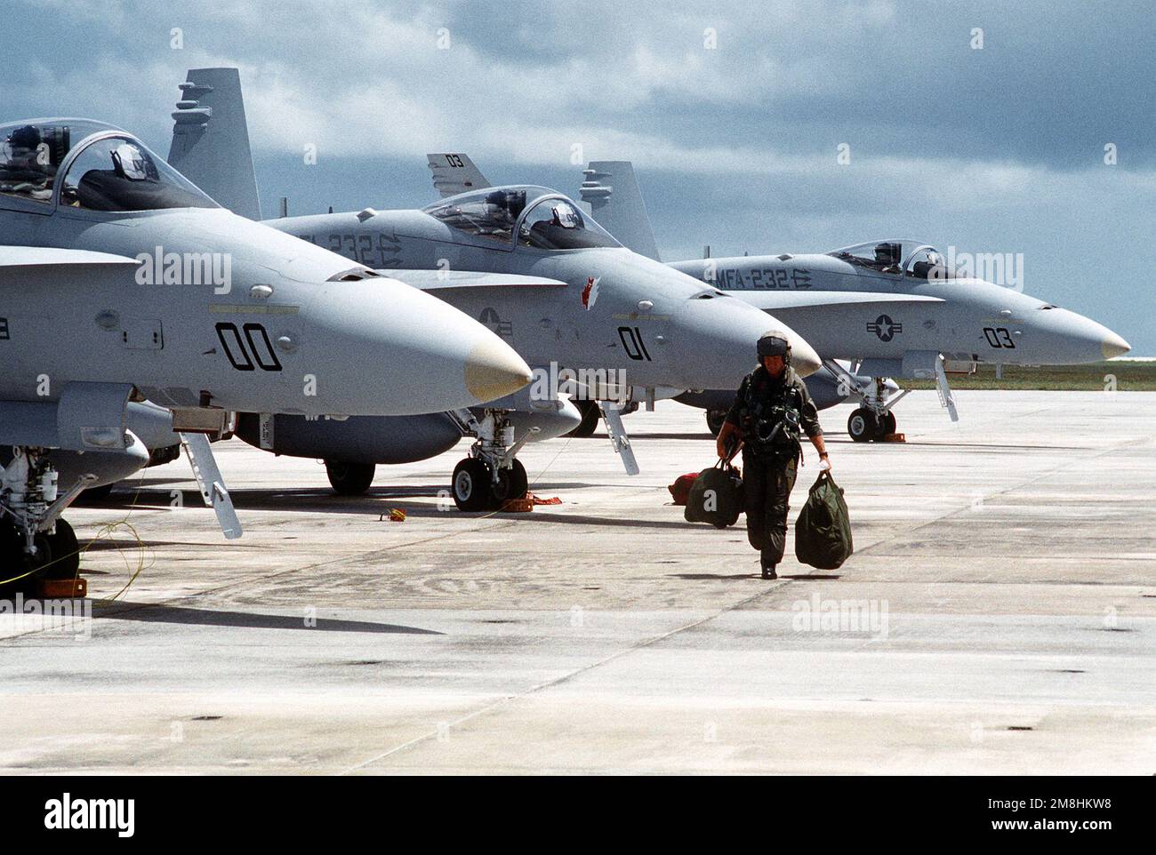 A pilot carries his gear across the flight line after disembarking from ...