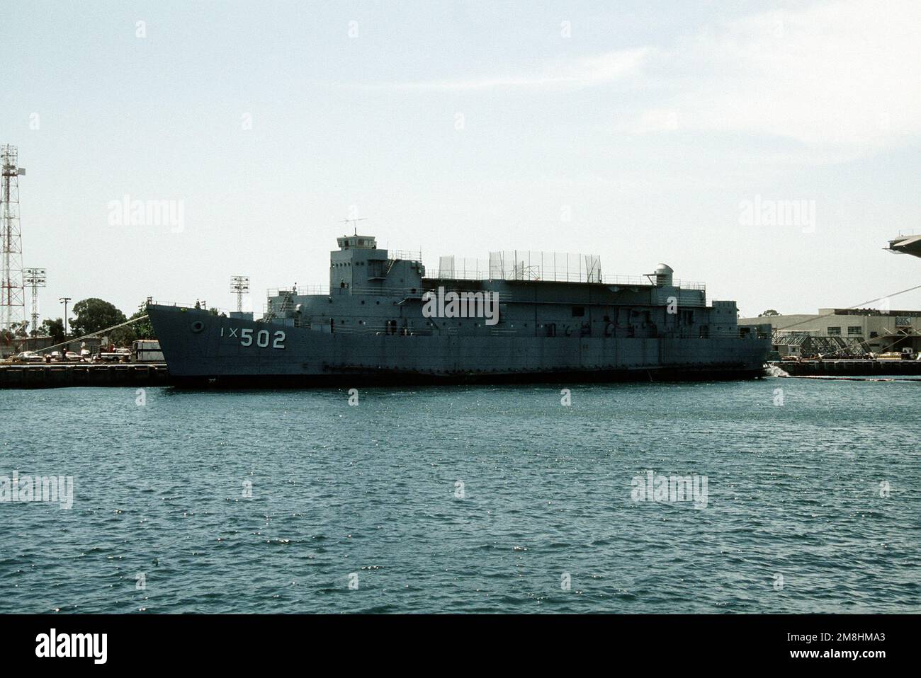 A port view of the barracks ship MERCER (IX-502) tied up at the pier ...