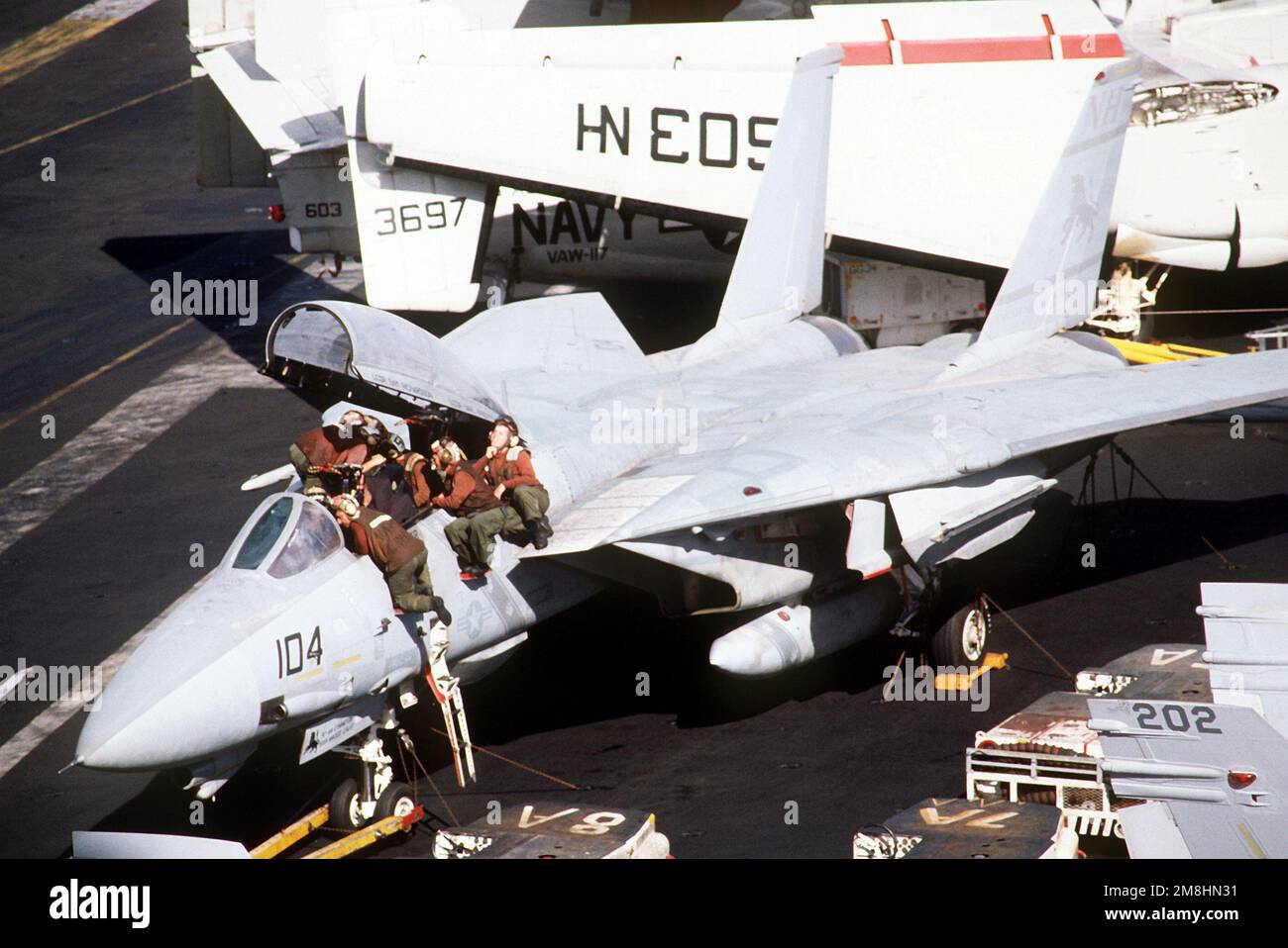 Flight deck crewmen are seen checking out an F-14A Tomcat aircraft of ...