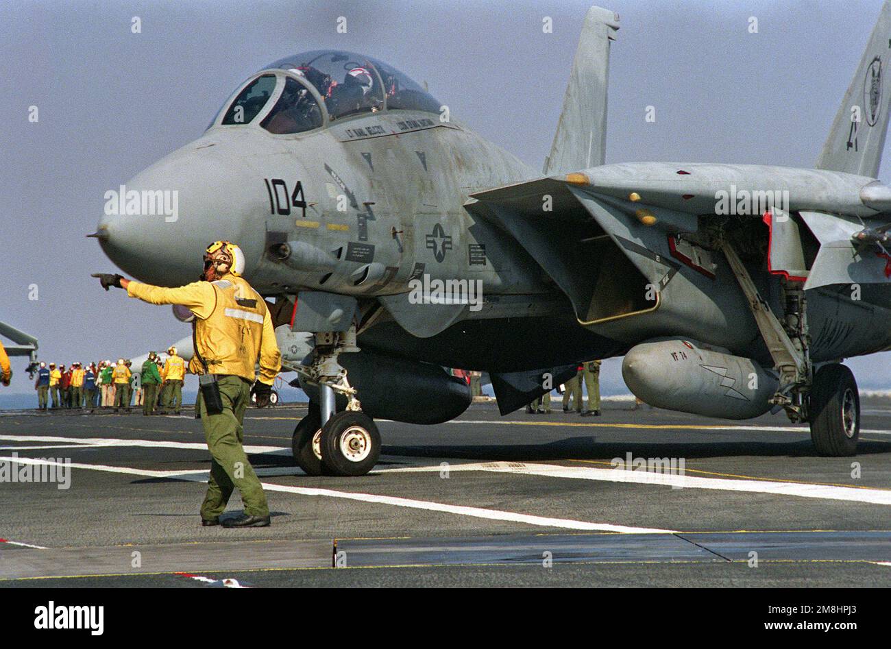 An F-14B Tomcat aircraft of Fighter Squadron 74 (VF-74) is directed across the flight deck ...