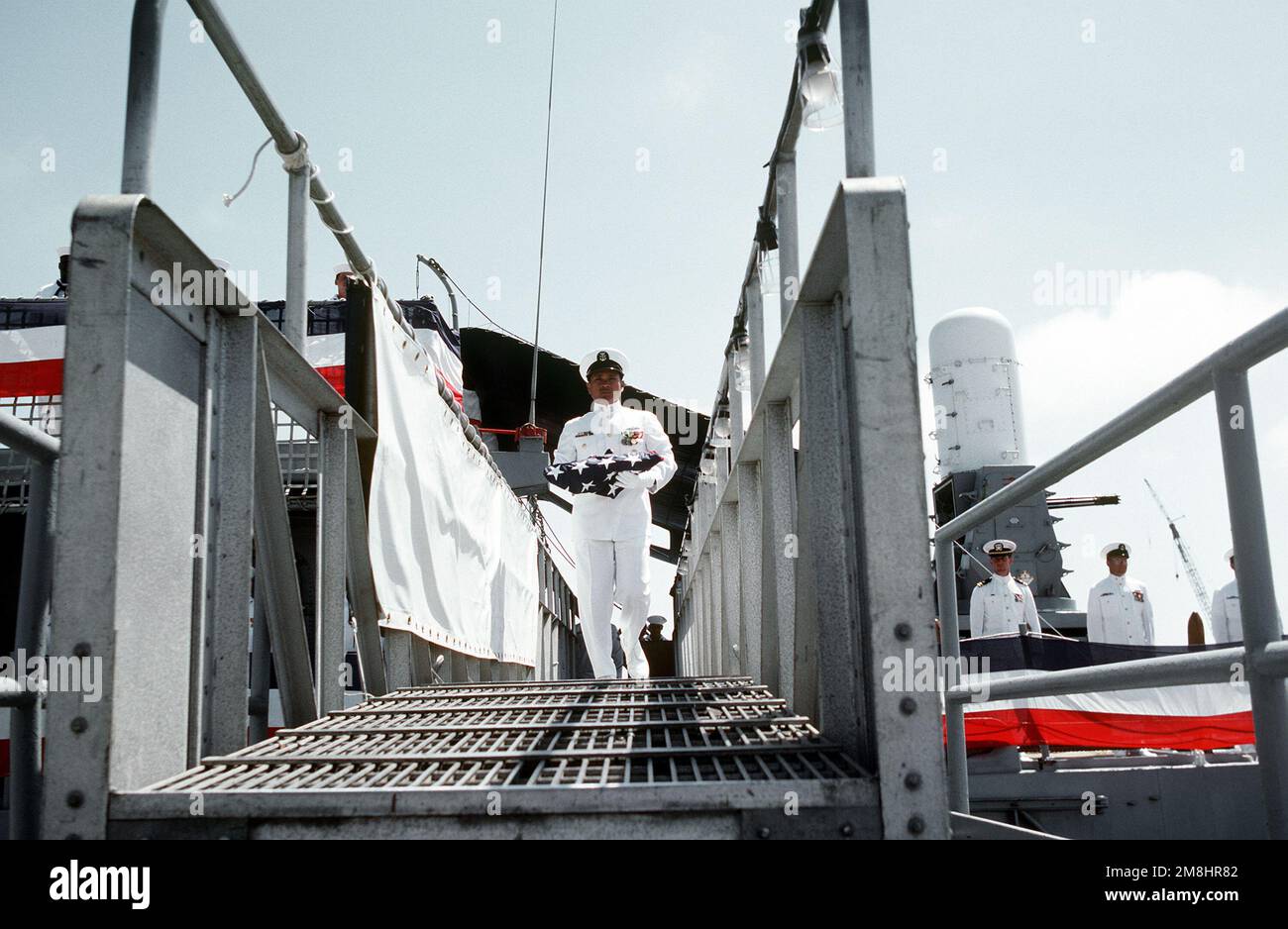 An officer carries the national ensign down the gangway of the former ...