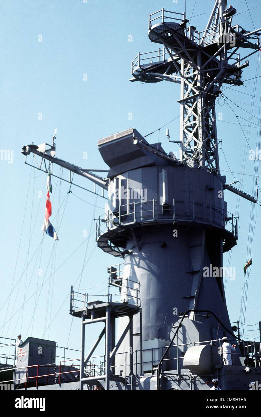 A crew member lowers the ship's pennants from the superstructure of the ...