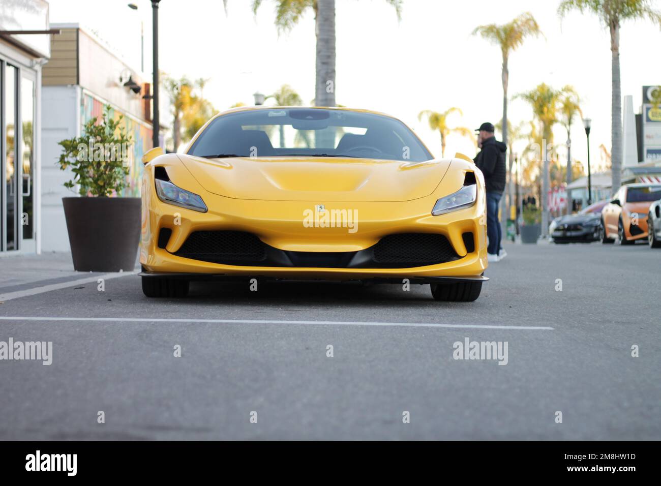 The front of a yellow car on the street getting ready for a car show in ...