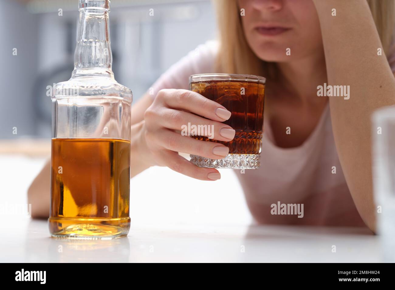 Drunk woman holding glass of whiskey and alcoholics alone Stock Photo - Alamy