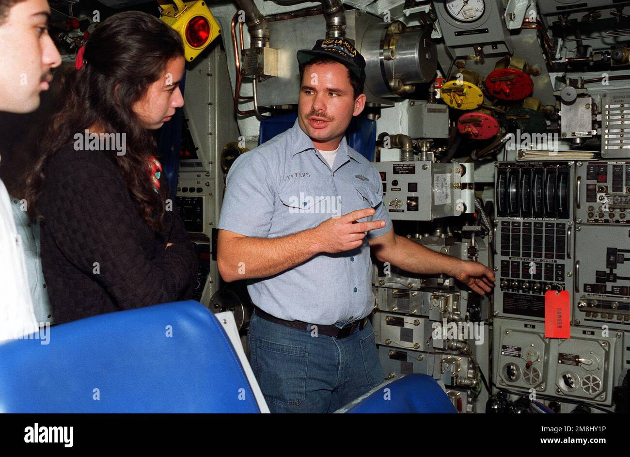 A crewman explains submarine operations to students visiting the ...