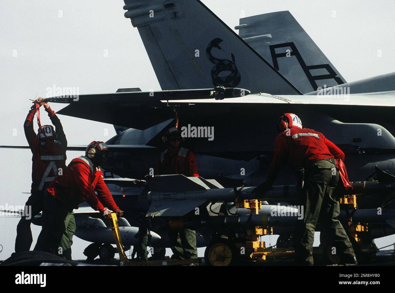 Ordnance personnel load a AIM-9L Sidewinder missile onto an F/A-18 ...