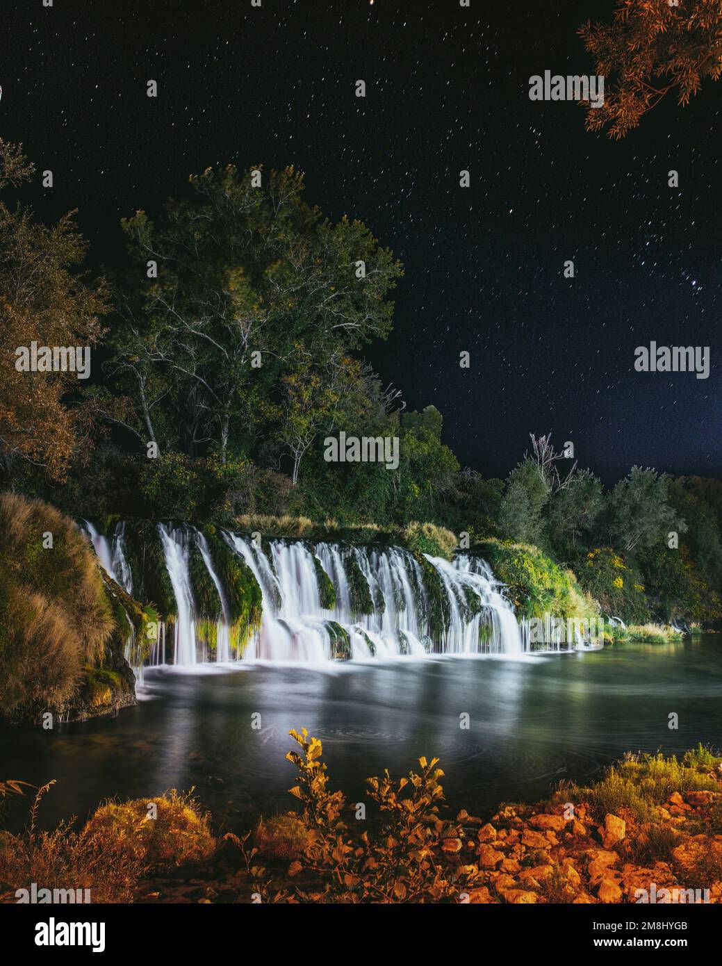 A vertical of waterfall view at night, stars in the dark sky background ...