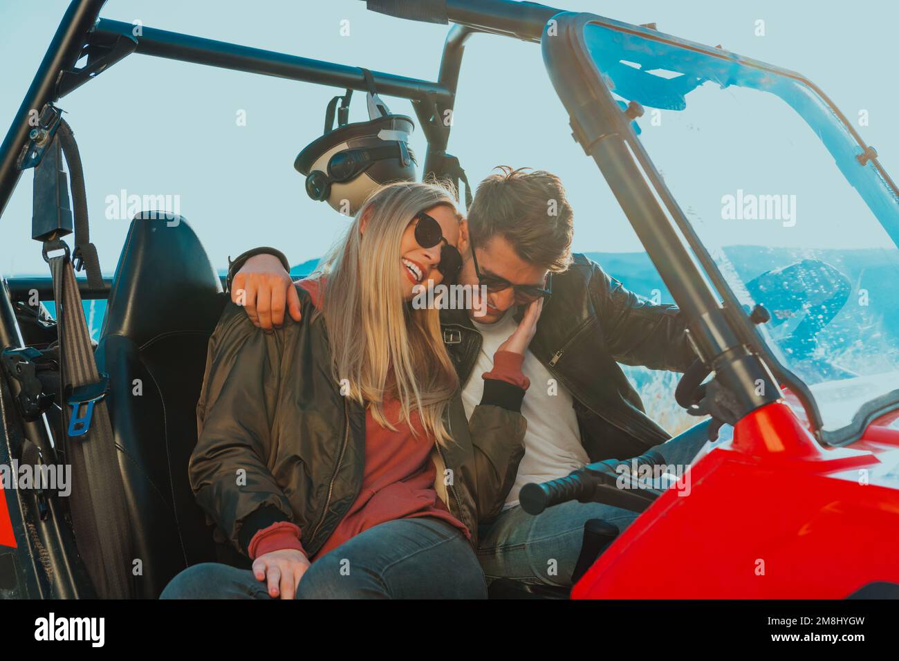 Young happy excited couple enjoying beautiful sunny day while driving a off road buggy car on ...