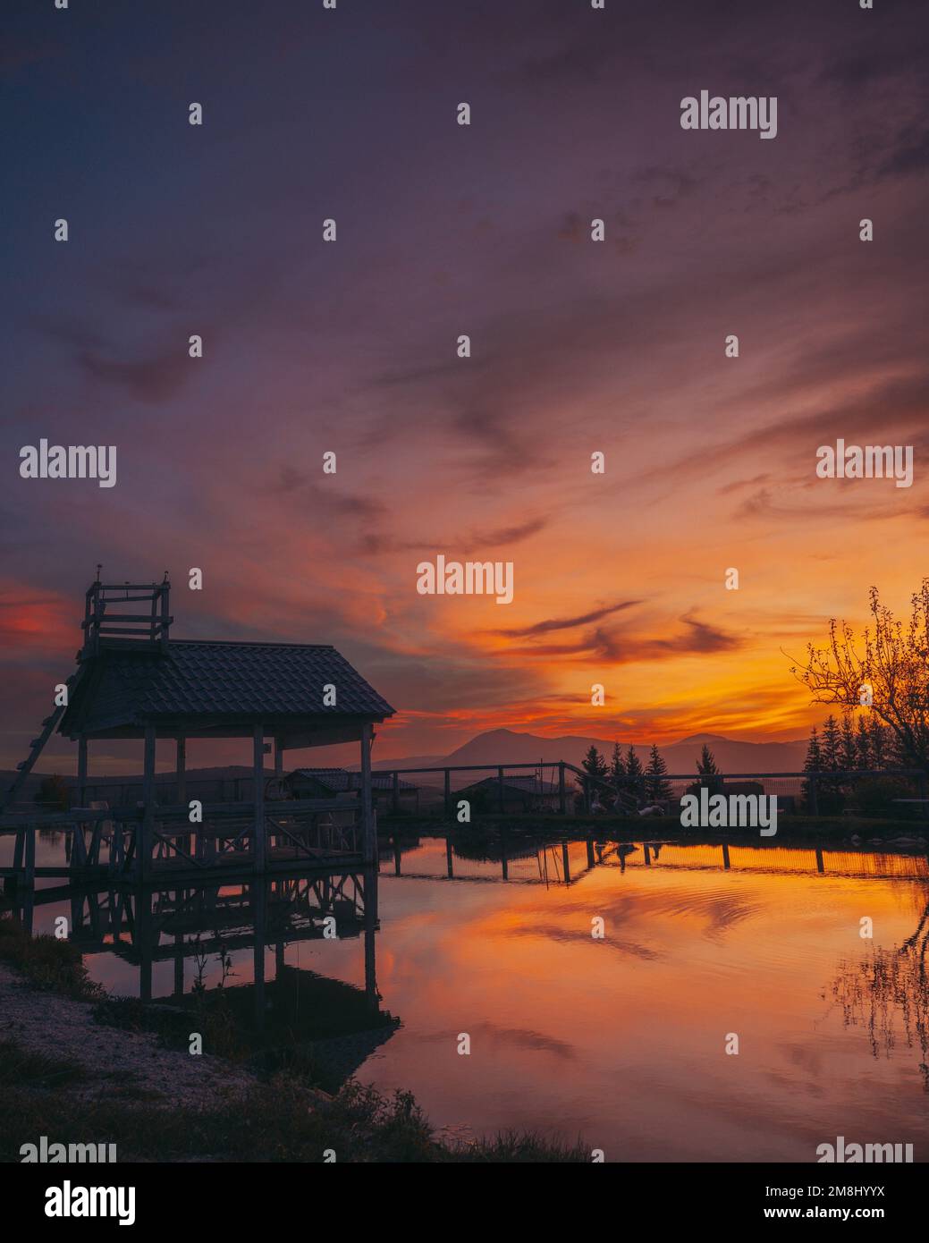 A vertical of a wooden building near lake view at sunset, purple ...