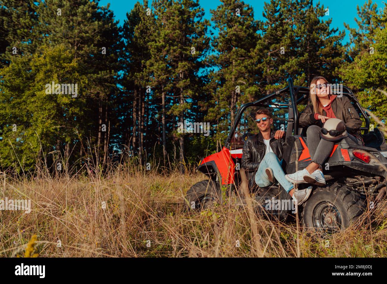Young happy excited couple enjoying beautiful sunny day while driving a off road buggy car on ...