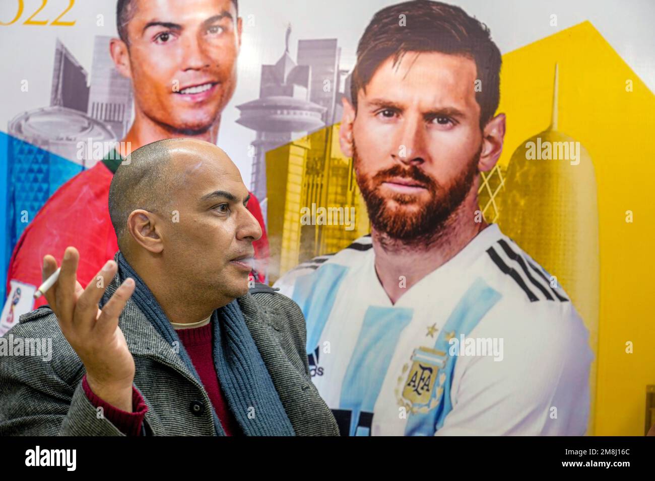 An Egyptian smokes a cigarette in front of a poster showing famous ...