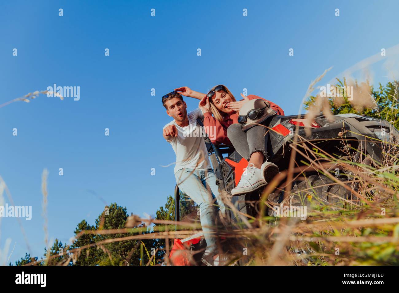 Young happy excited couple enjoying beautiful sunny day while driving a off road buggy car on ...