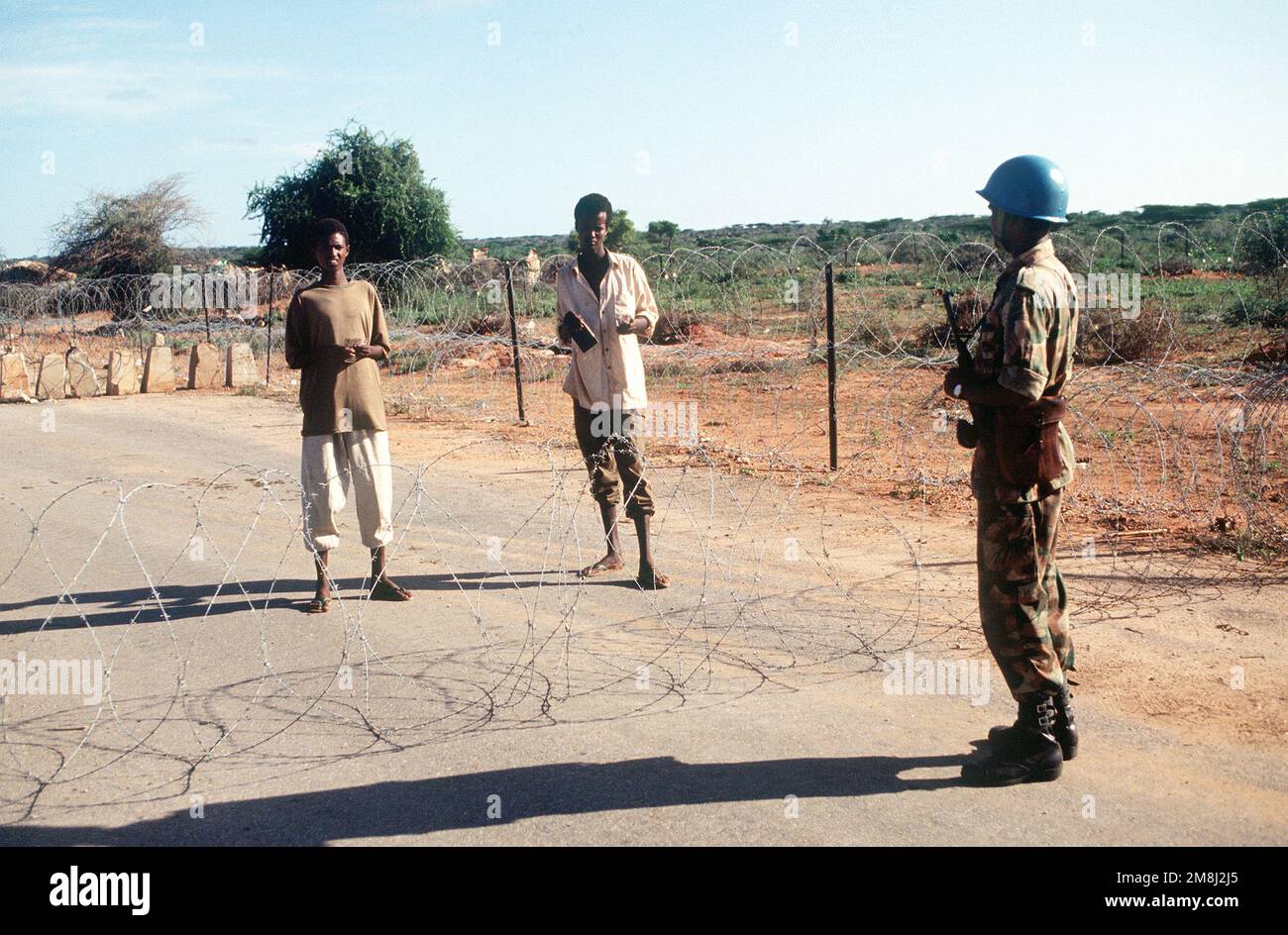 A Indian soldier on guard duty at the airport in Kismayo. Concertina ...