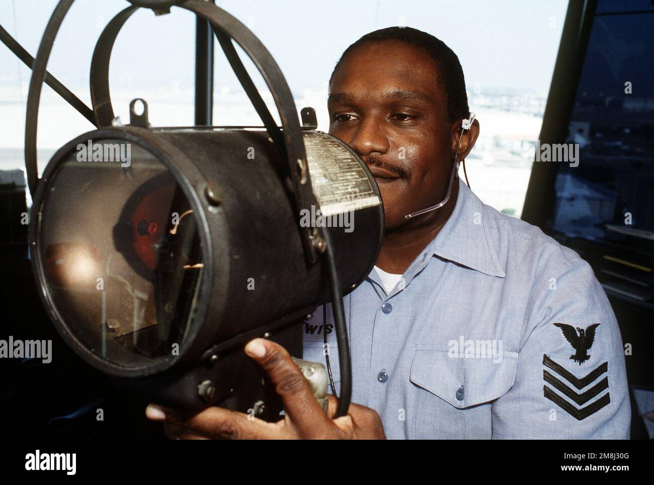 Air Traffic Controlman Third Class (AC1) Gregory Lewis uses a signal ...