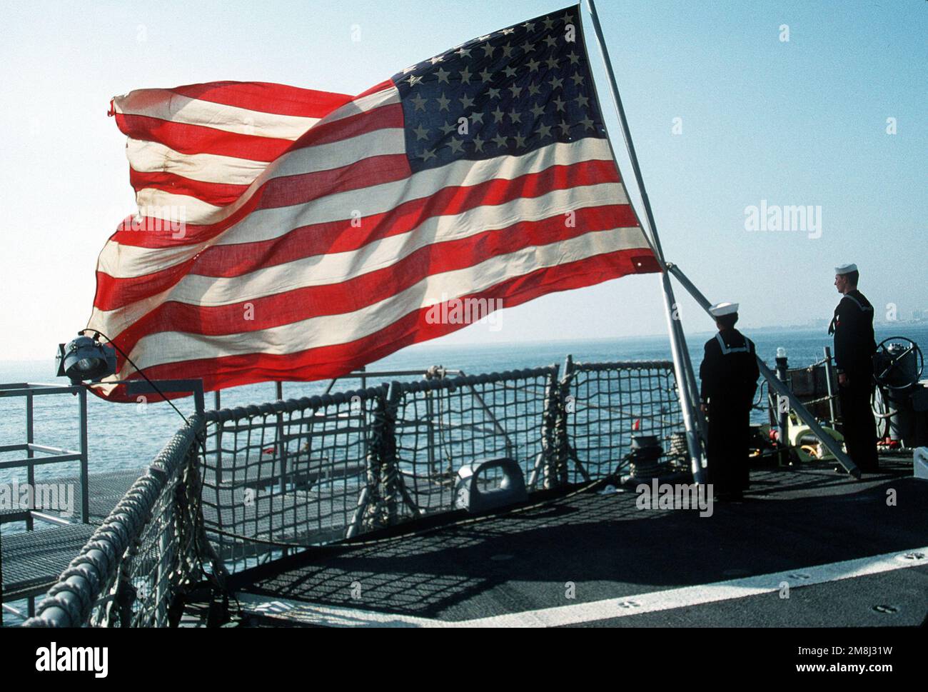 A large holiday National ENSIGN flies from the fantail of the guided ...