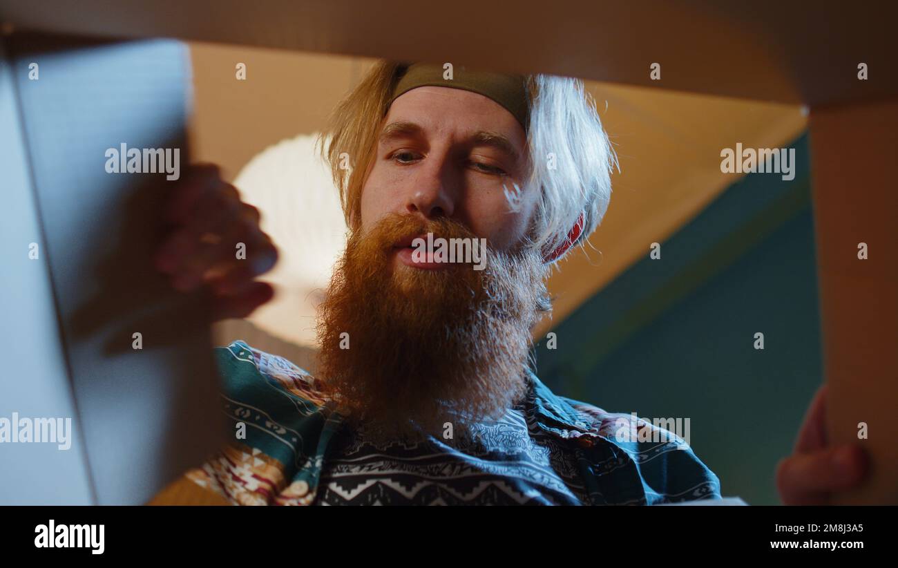 Happy surprised winner man unpacking delivery parcel at home. Smiling ...