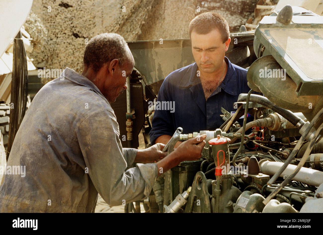 A German soldier trains a Somali man on engine repair. The German ...