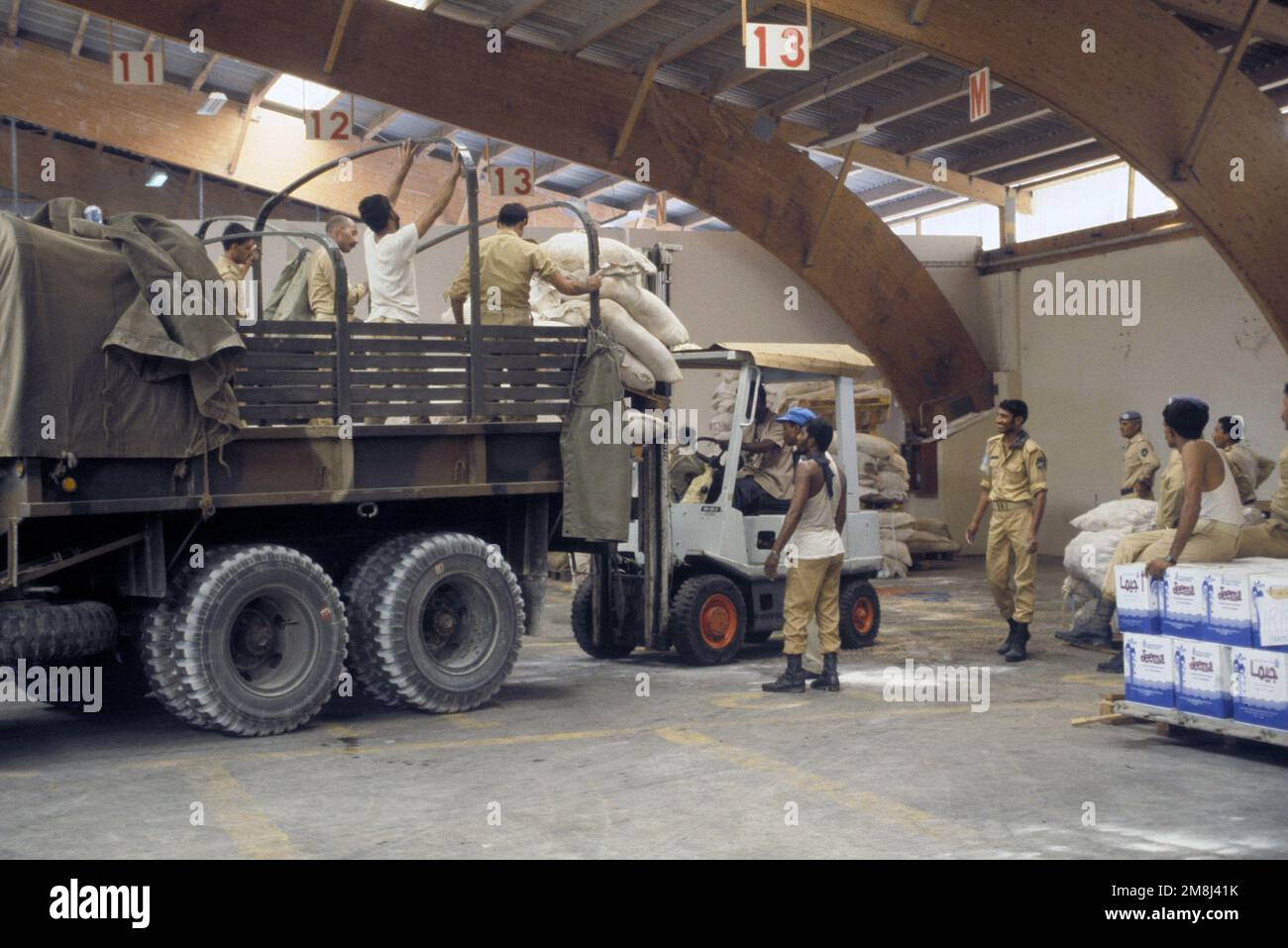 Soldiers use a forklift to load food supplies onto a 2-1/2 ton truck in ...