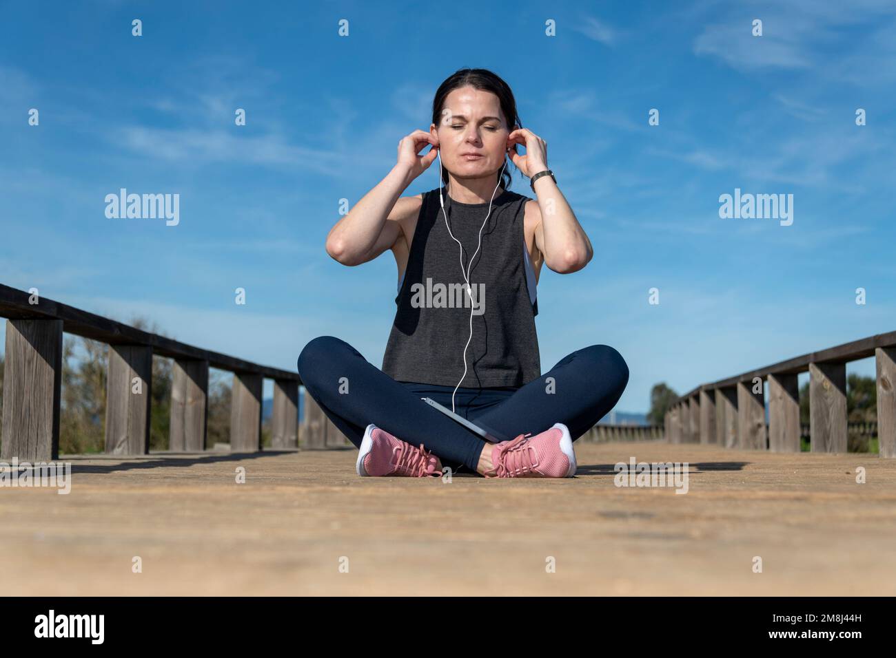 Female runner resting after exercise, sitting listening to music Stock ...