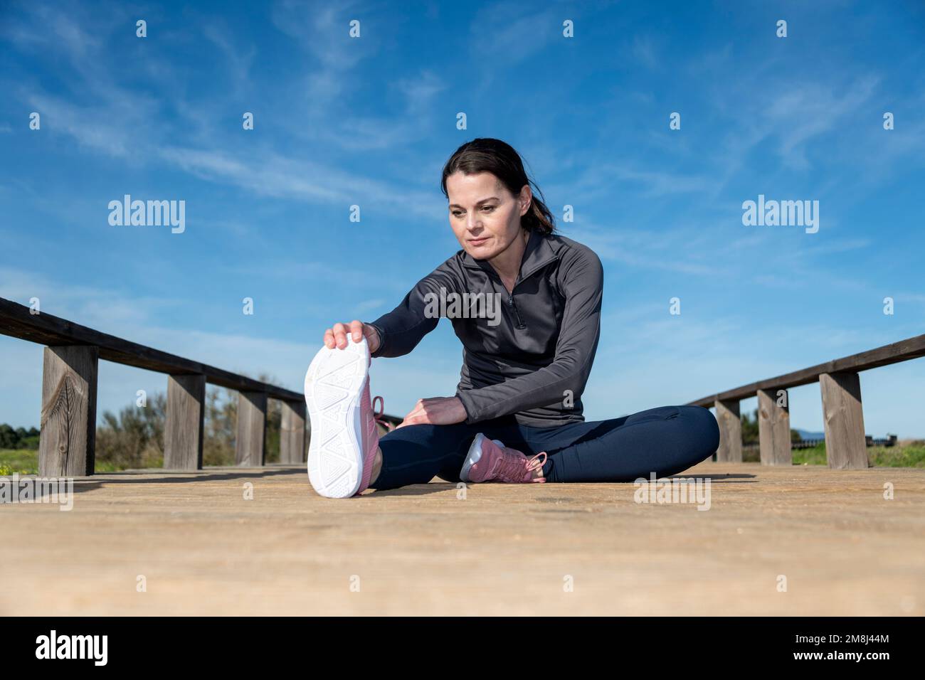 Sporty female doing sitting doing a leg stretch warm up exercise before ...
