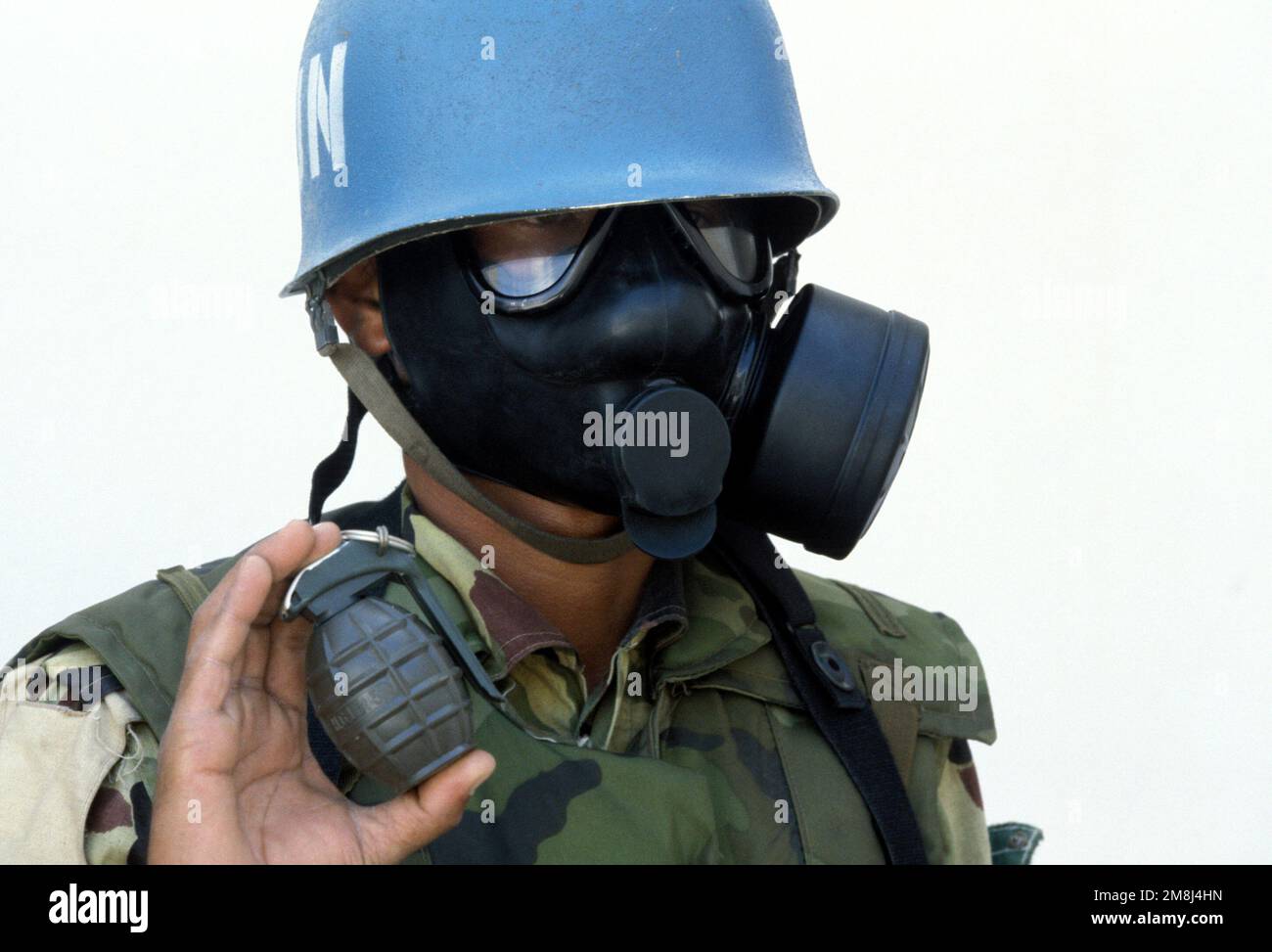 A Nepalese soldier clad in a protective mask displays a CS gas grenade ...