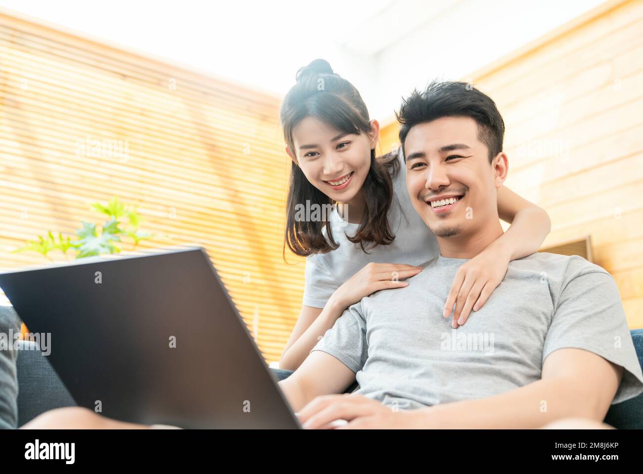 Young couples to use a computer on the sofa Stock Photo - Alamy