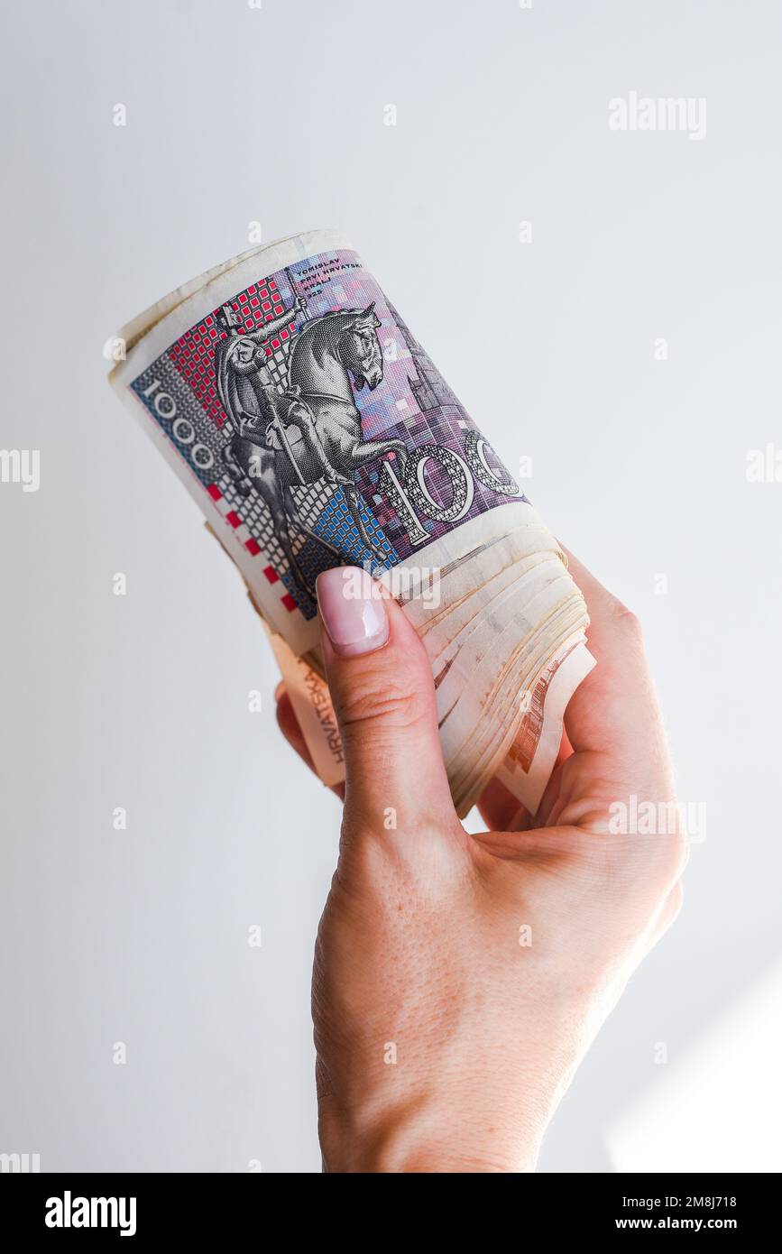 A human hand holding the Croatian kuna banknotes against the white wall ...