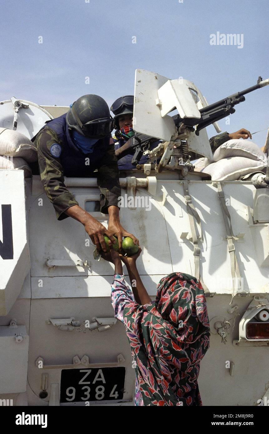 A Somali woman sells mangos to Melanesian soldiers in an armored ...