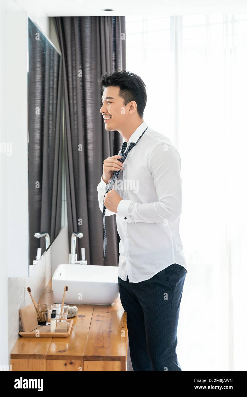 A young man in front of the mirror tie Stock Photo - Alamy
