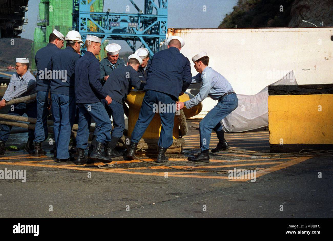 Members of the base force are shown hauling in mooring lines to secure ...