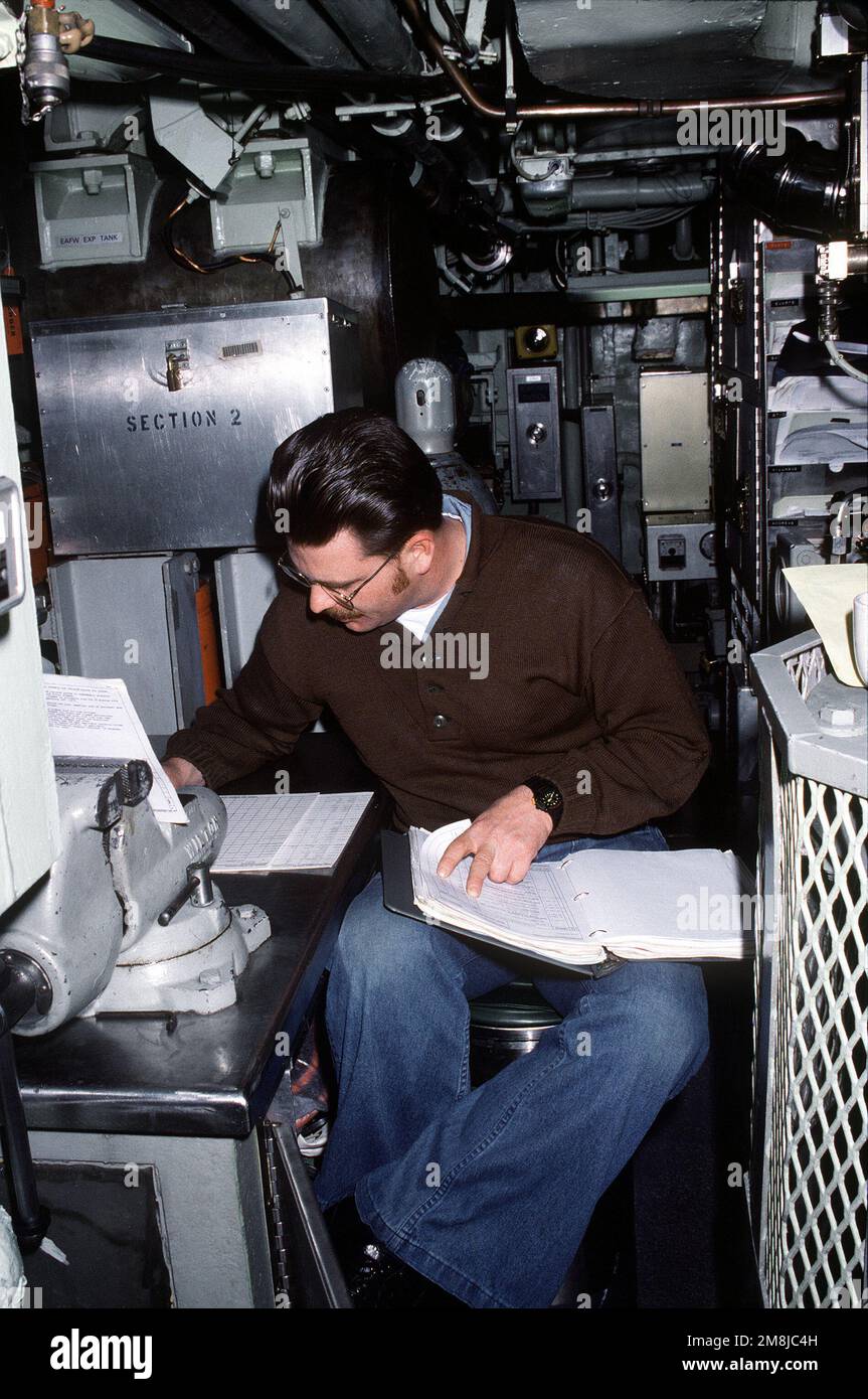Machinist Mate First Class (MM1) Robert Ramos is shown writing up the ...