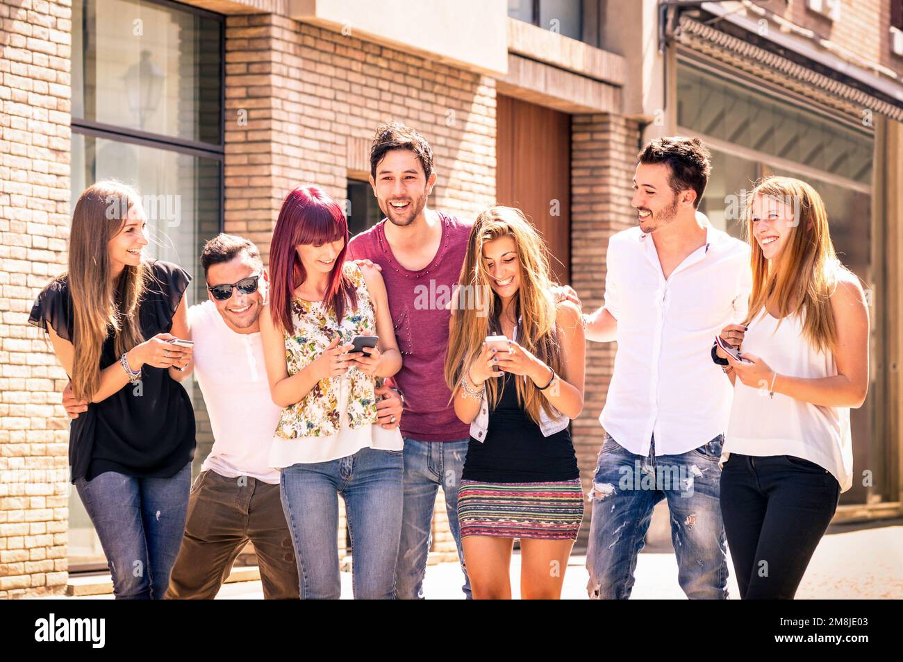 Group of young best friends having fun together walking on town street ...