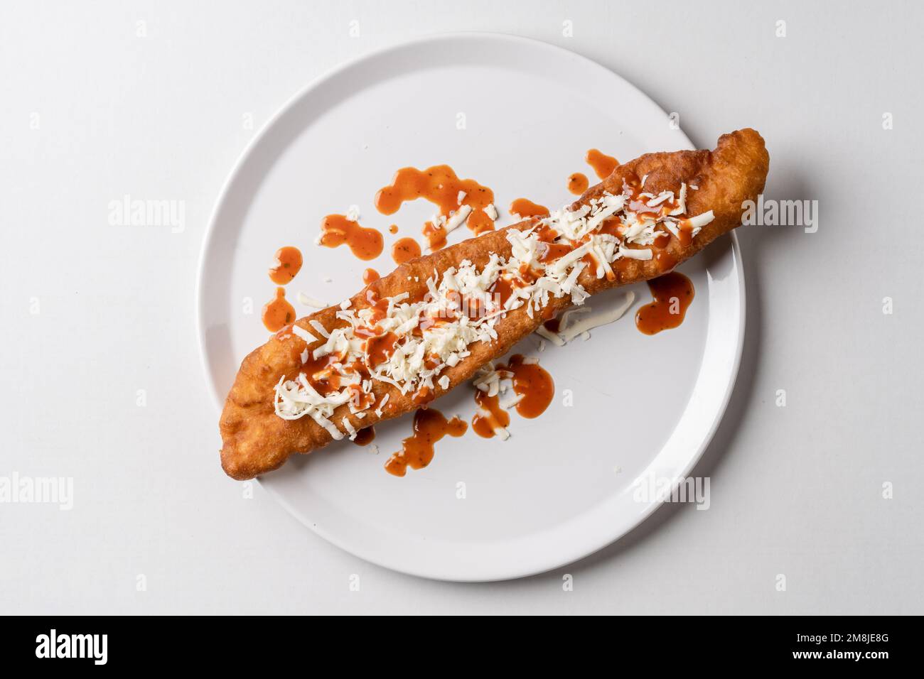 Top down on fried dough stick in white plate Mekitsa or mekika ...