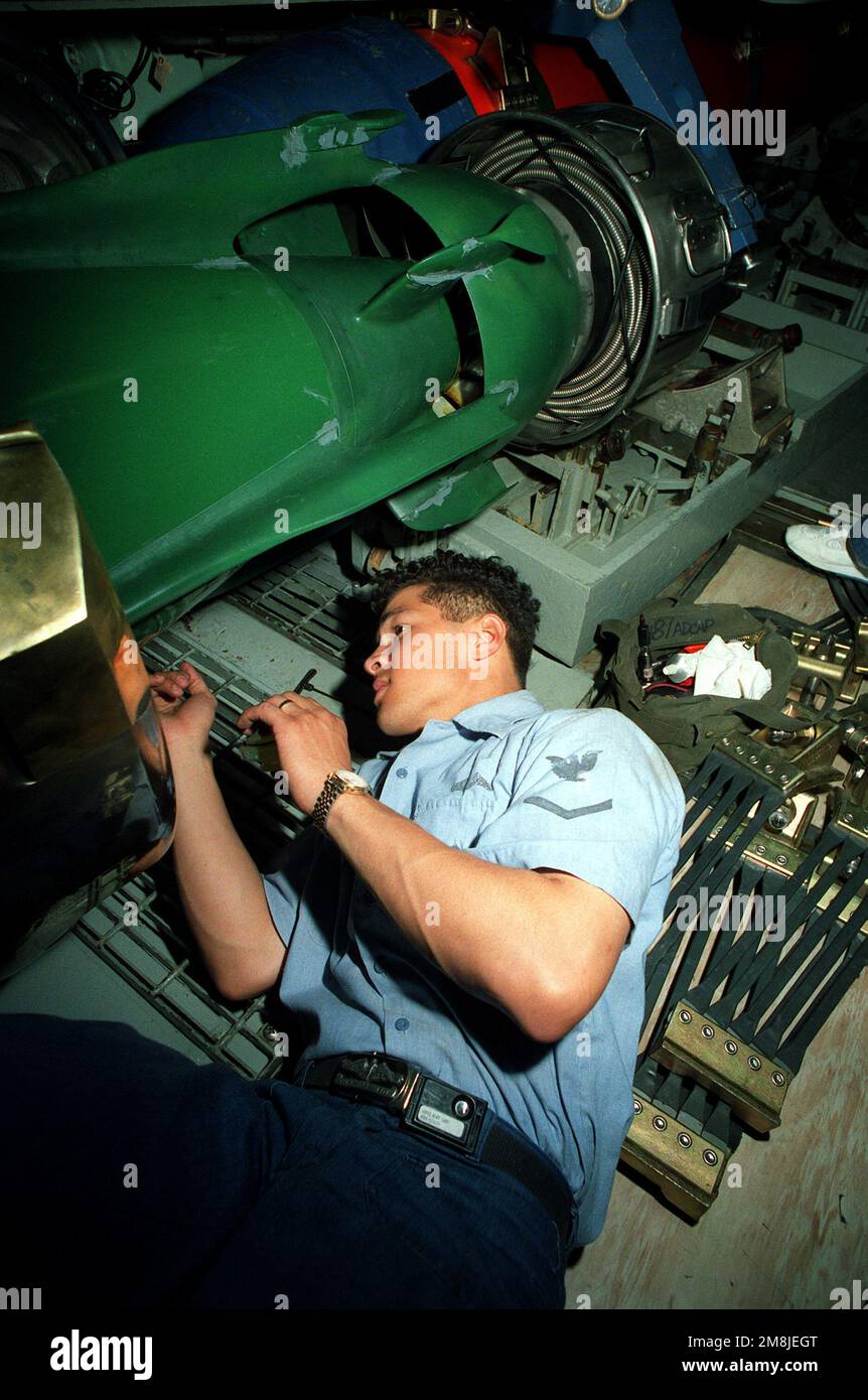 Torpedoman Third Class (TM3) Kurt Lopez attaches an "A" cable to an ...