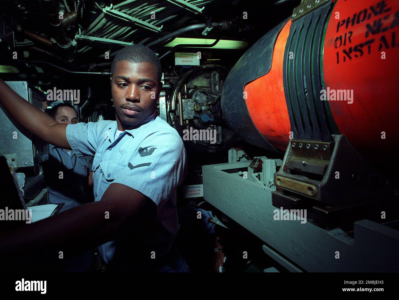 Torpedoman Third Class (TM3) Greg Culbreath runs the rammer as a team ...