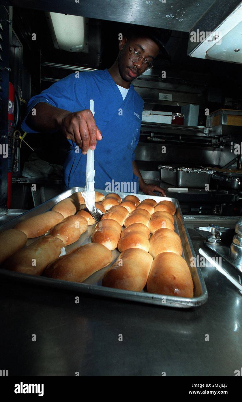 Mess SPECIALIST Third Class Raymond Shields brushes butter on to ...