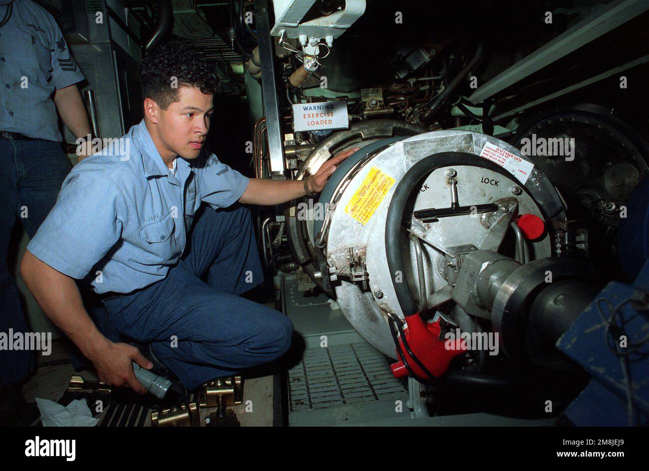 Torpedoman Third Class (TM3) Kurt Lopez observes the removal of a ...