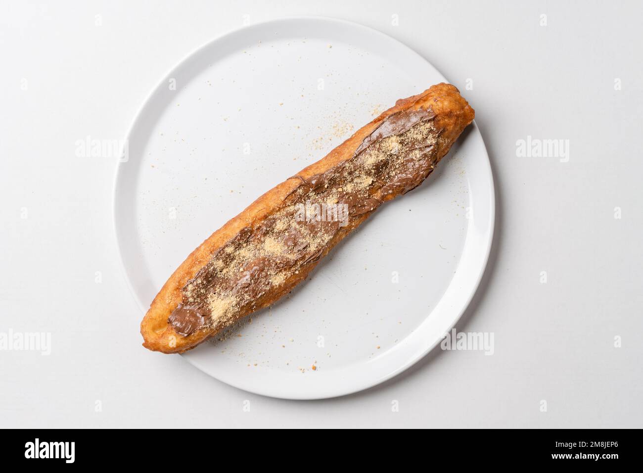 Top down on fried dough stick in white plate Mekitsa or mekika ...
