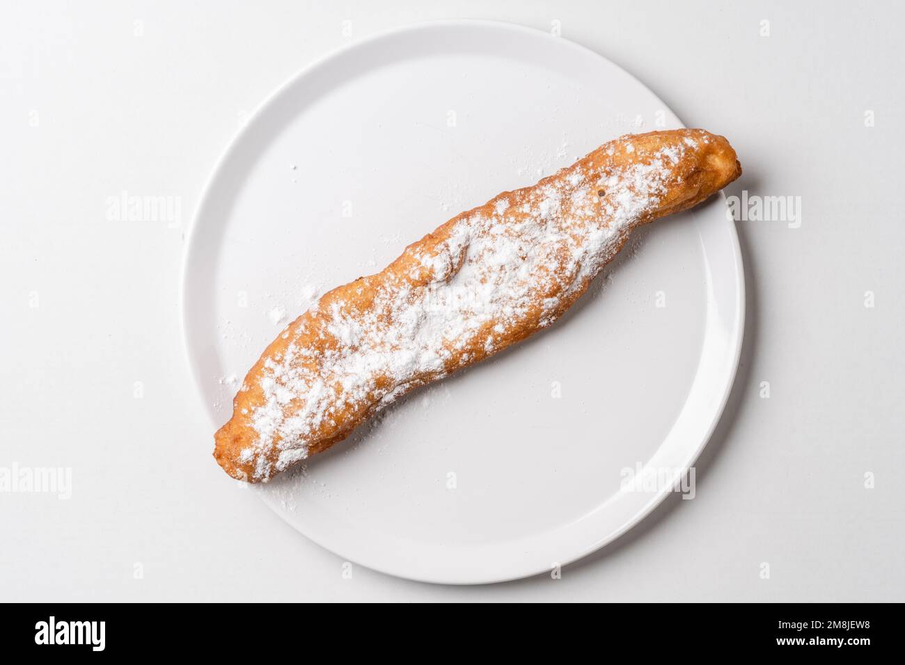 Top down on fried dough stick in white plate Mekitsa or mekika ...