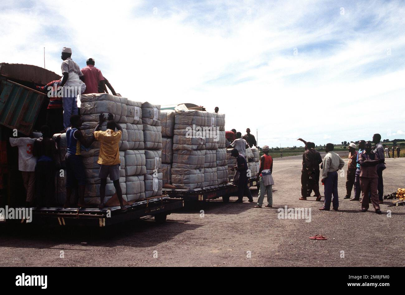 Local personnel break down pallets and load trucks with supplies that ...