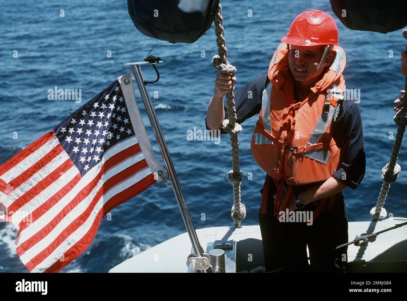 A seaman stands by during preparations to hoist the rigid rubber boat ...