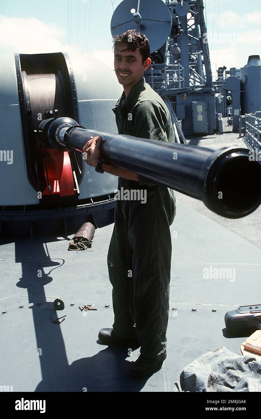 Gunners Mate Guns Third Class (GMG3) James Clark is shown assisting ...