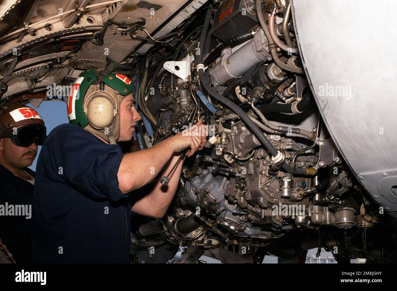 Aviation Machinist Third Class (AD3) Ron Swager repairs the engine of a ...