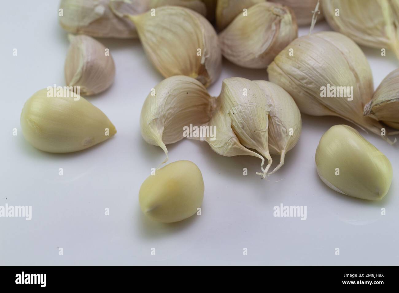 close up of peeled and unpeeled garlic isolated on white background ...